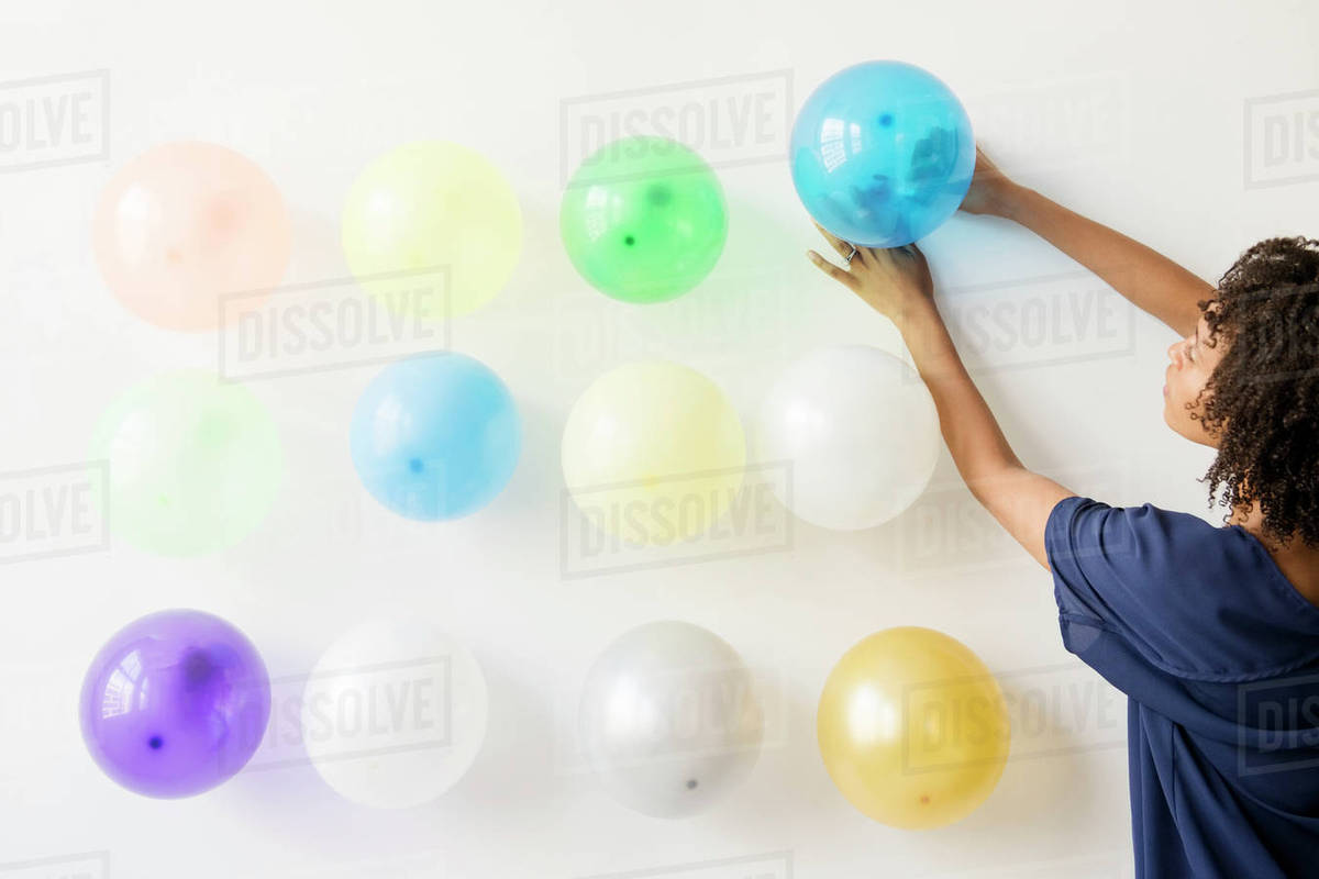 Black woman attaching balloons to wall - Royalty-free Stock Photo ...