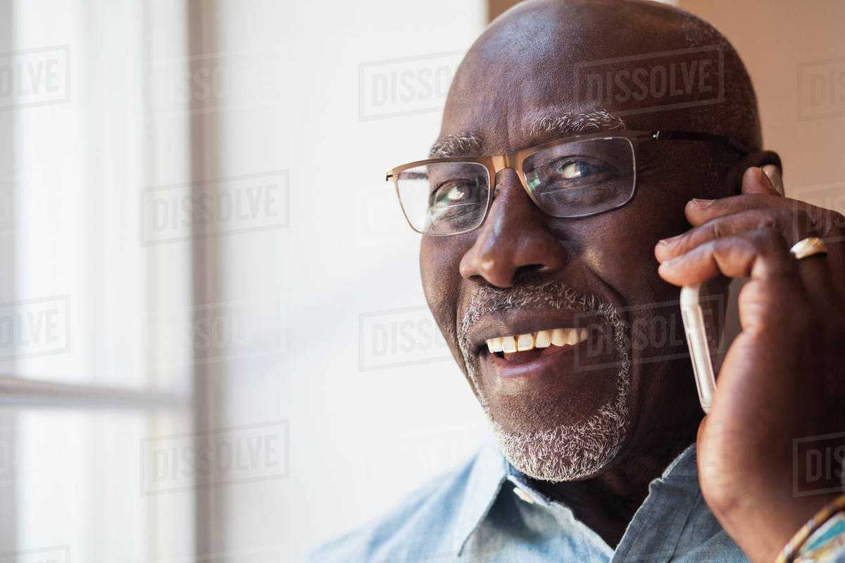 Man talking on cell phone near window - Stock Photo - Dissolve