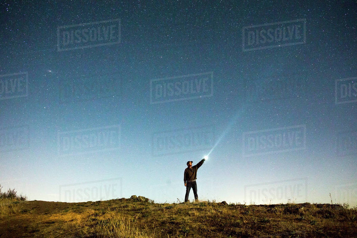 Caucasian man pointing flashlight at night sky - Stock Photo - Dissolve