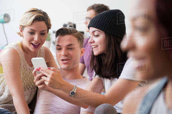 Smiling friends texting on cell phone - Stock Photo - Dissolve