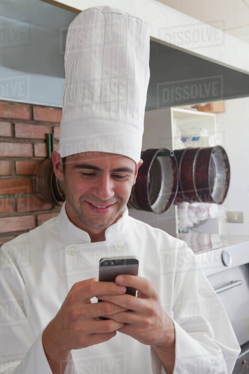 Smiling Hispanic chef texting on cell phone - Royalty-free Stock Photo ...