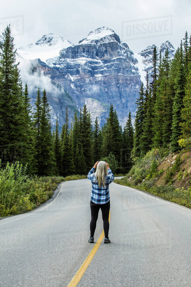 Caucasian woman standing in road photographing mountain - Stock Photo ...