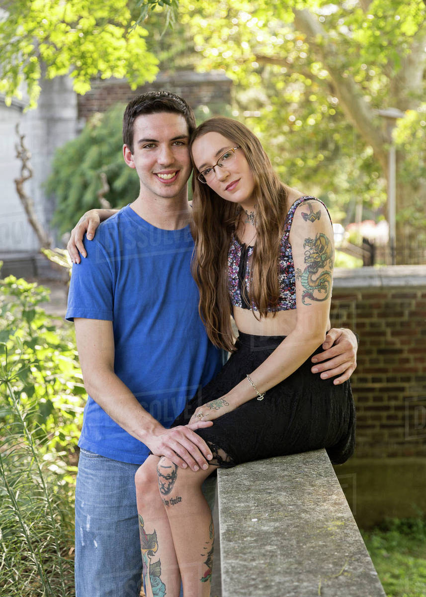Caucasian couple posing on wall at park - Royalty-free Stock Photo ...