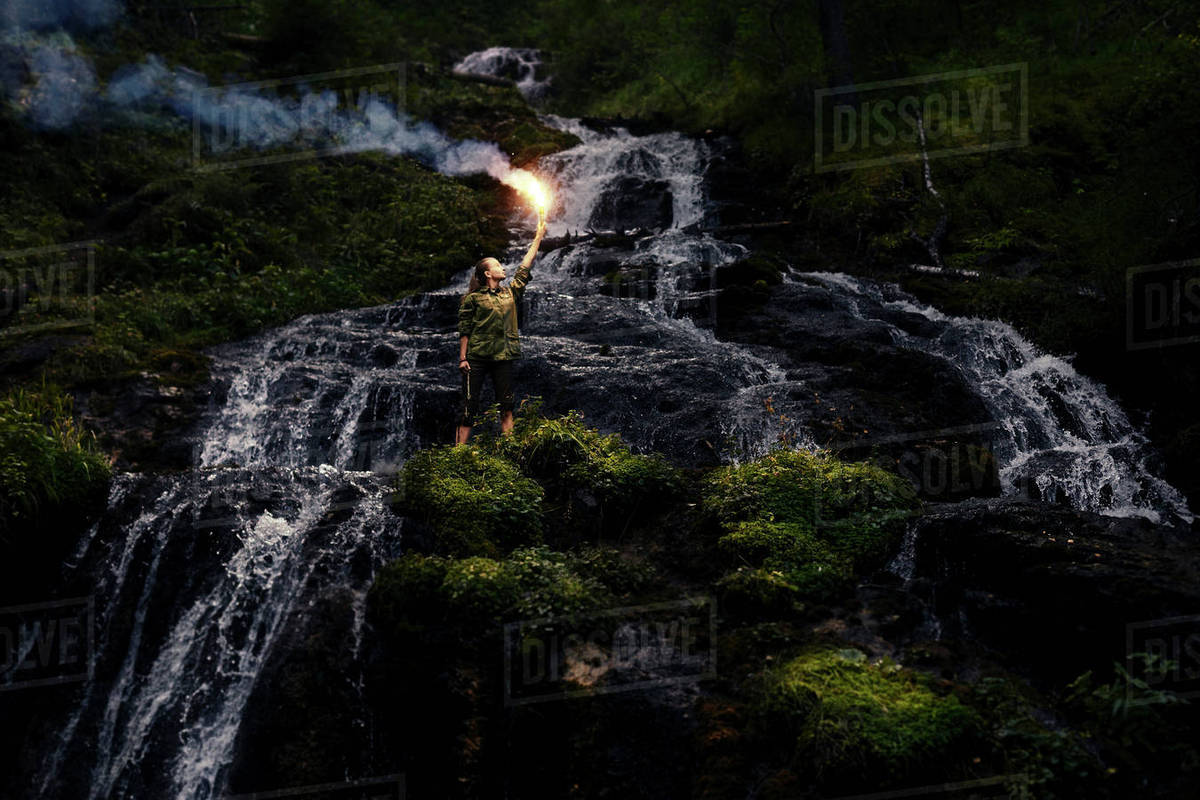 Caucasian girl holding smoke flare near waterfall - Royalty-free Stock ...
