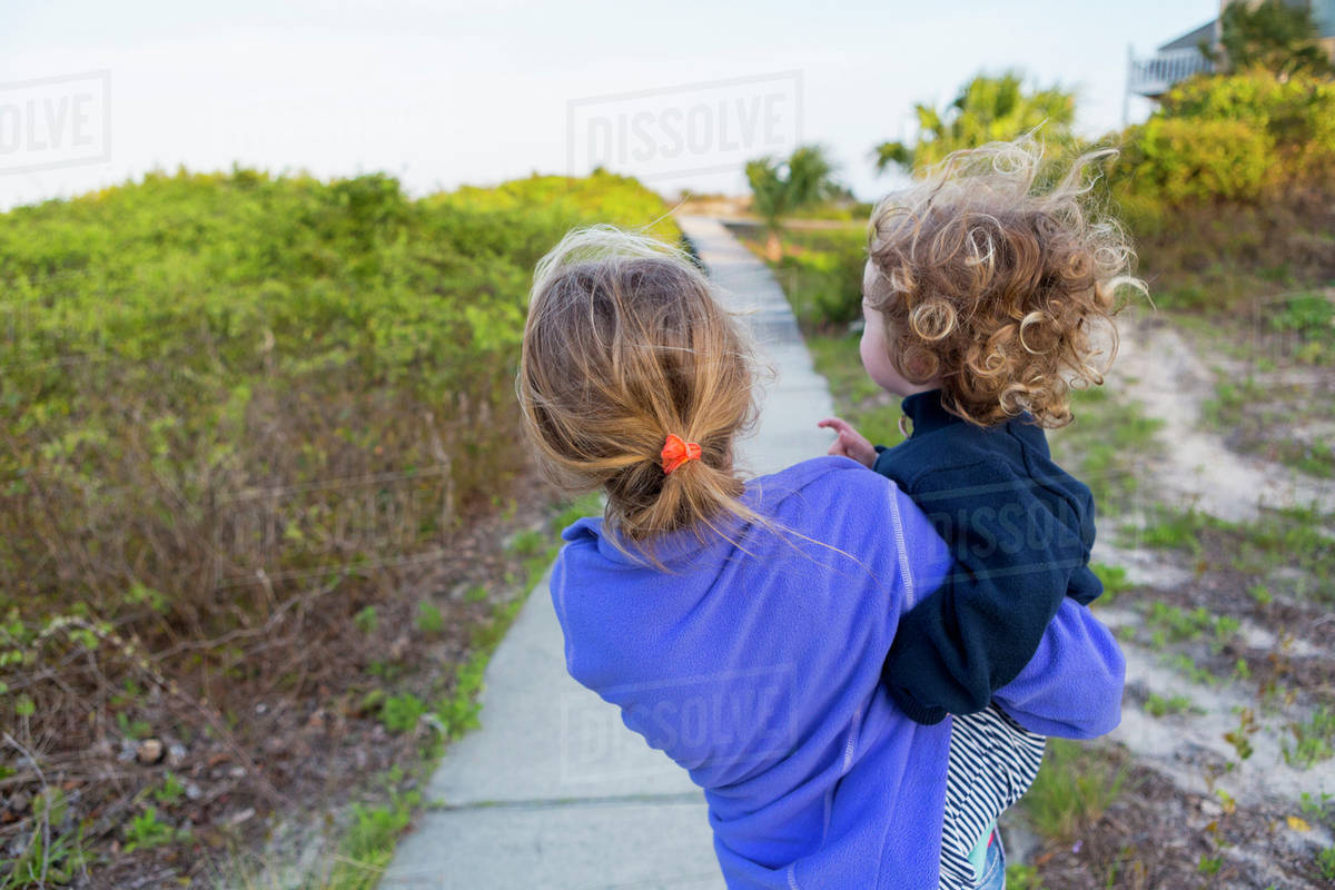 Caucasian girl carrying baby brother on wooden walkway - Royalty-free ...