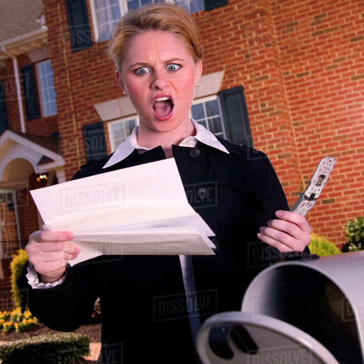 Angry woman reading mail at mailbox - Stock Photo - Dissolve