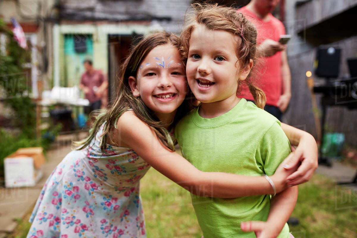 Girls hugging at backyard party - Stock Photo - Dissolve