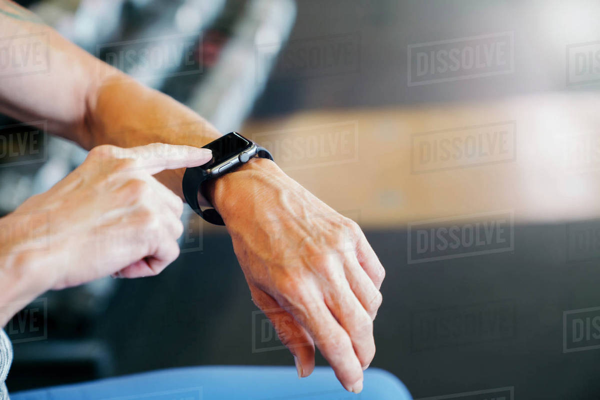 Woman tapping smart watch - Royalty-free Stock Photo | Dissolve