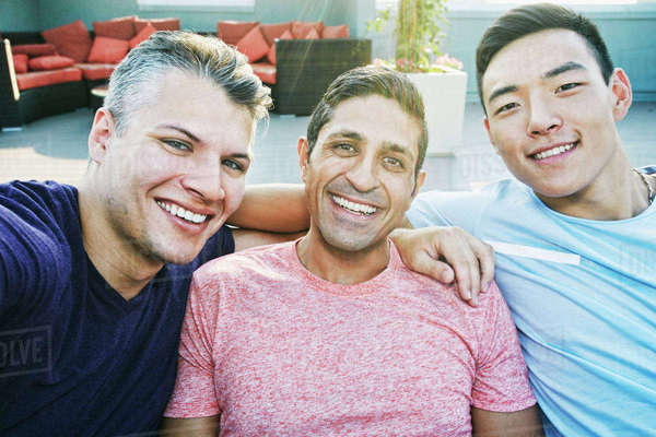 Smiling men posing on rooftop - Stock Photo - Dissolve