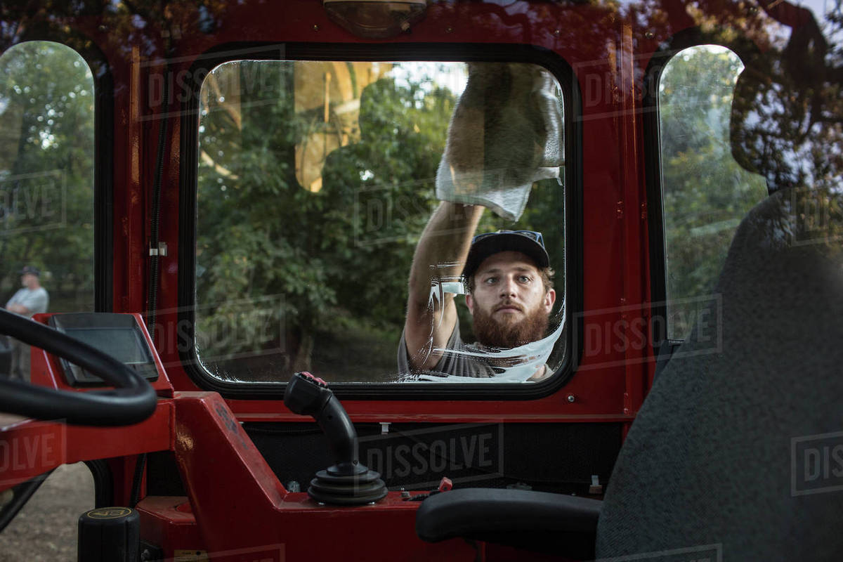 Man washing window of tractor - Stock Photo - Dissolve