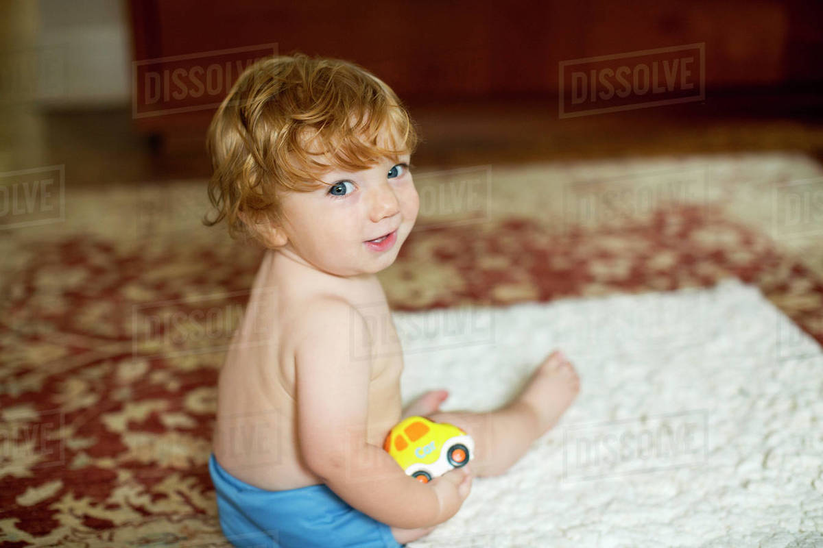 Baby boy sitting on rug holding toy car - Royalty-free Stock Photo ...