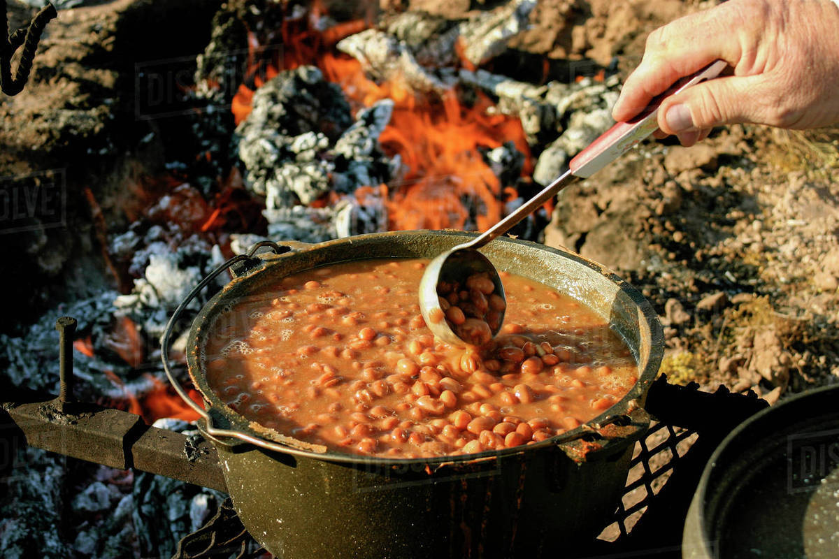 Hand of man stirring beans with ladle on campfire - Royalty-free Stock ...