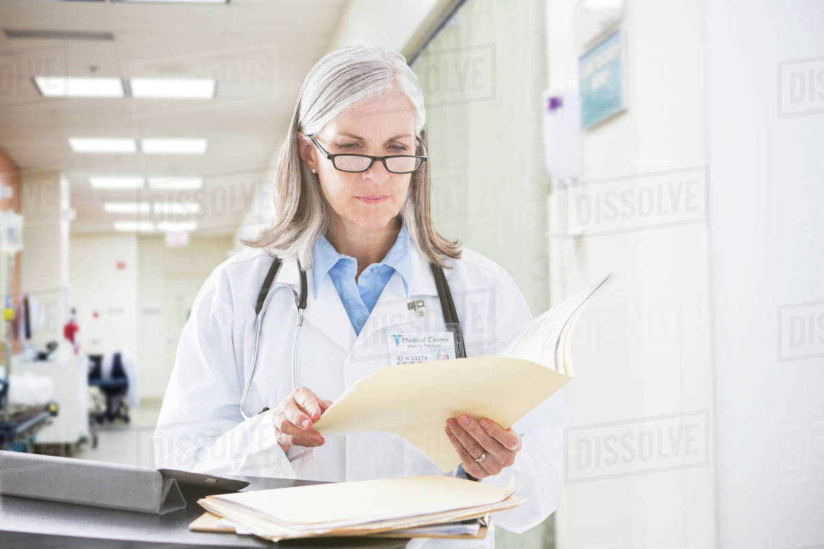 Caucasian doctor reading files in hospital - Royalty-free Stock Photo ...