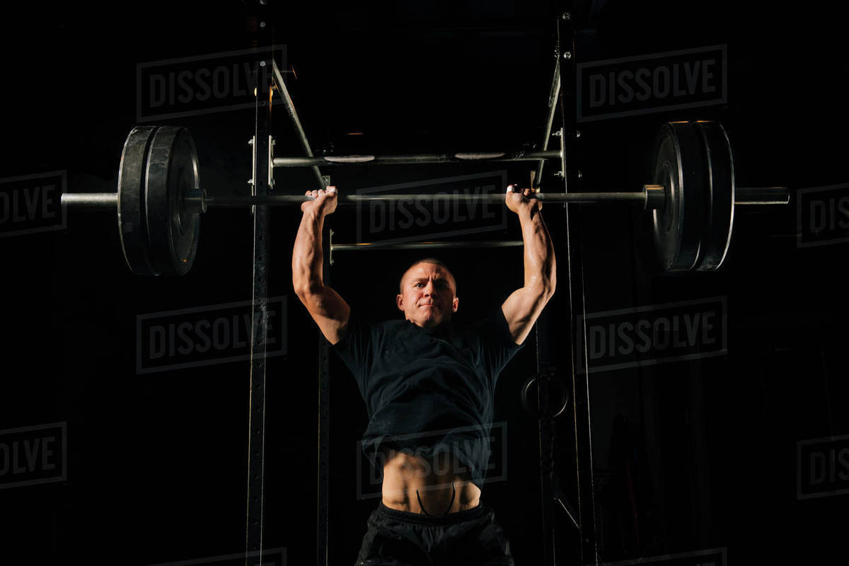 Man lifting heavy barbell in gymnasium - Royalty-free Stock Photo ...