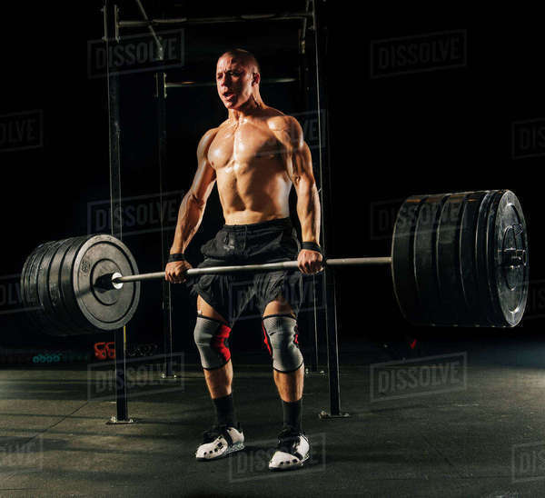 Man lifting heavy barbell in gymnasium - Royalty-free Stock Photo ...