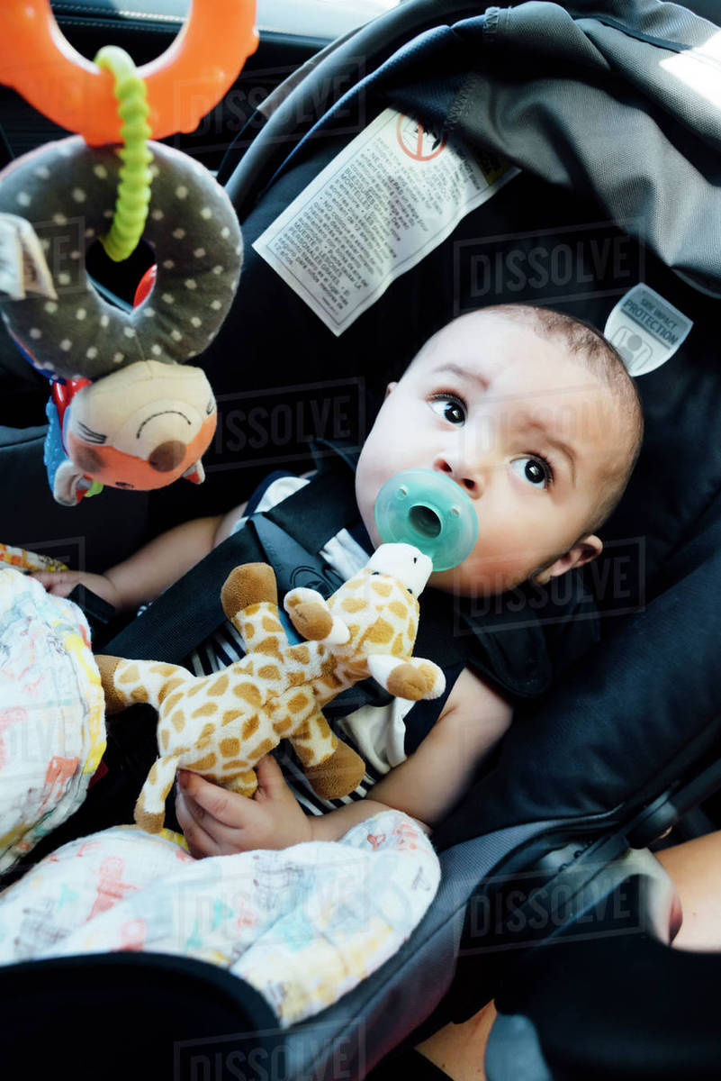 Curious Mixed Race baby boy with pacifier in car seat - Royalty-free ...