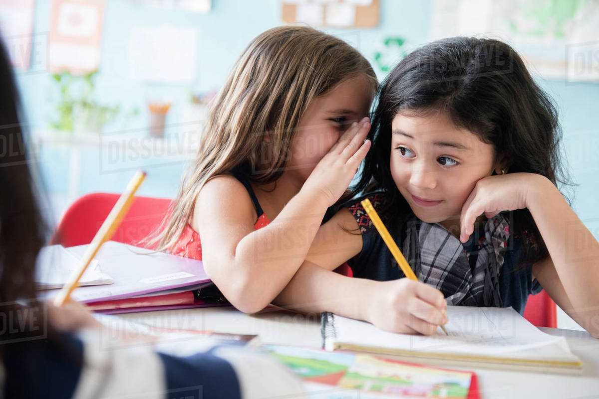Girl whispering to classmate in school - Royalty-free Stock Photo ...