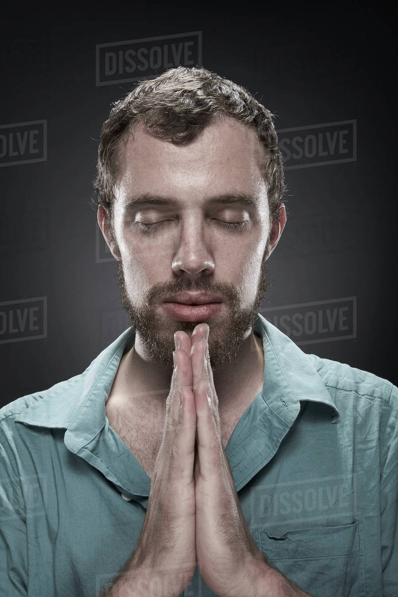 Serious man praying with eyes closed - Royalty-free Stock Photo | Dissolve