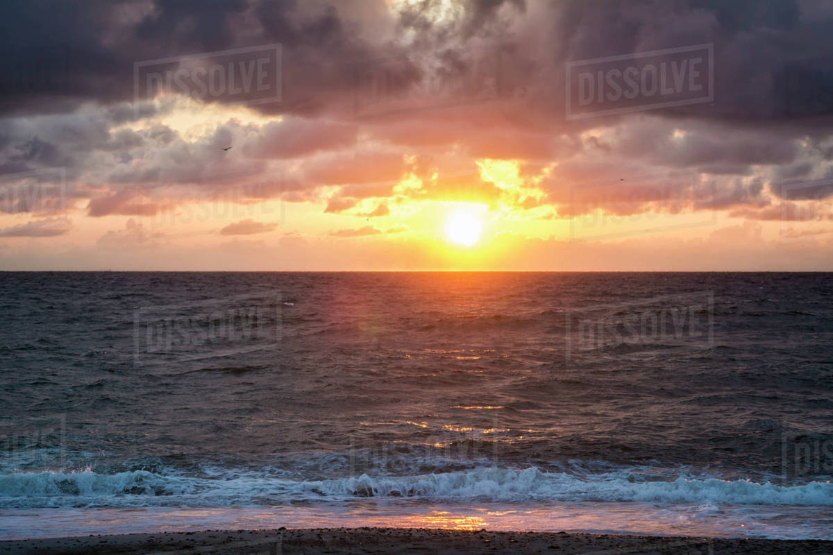 Ocean waves on beach at sunset - Royalty-free Stock Photo | Dissolve