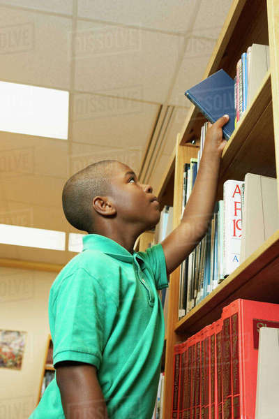 African American boy taking book off library shelf - Royalty-free Stock ...