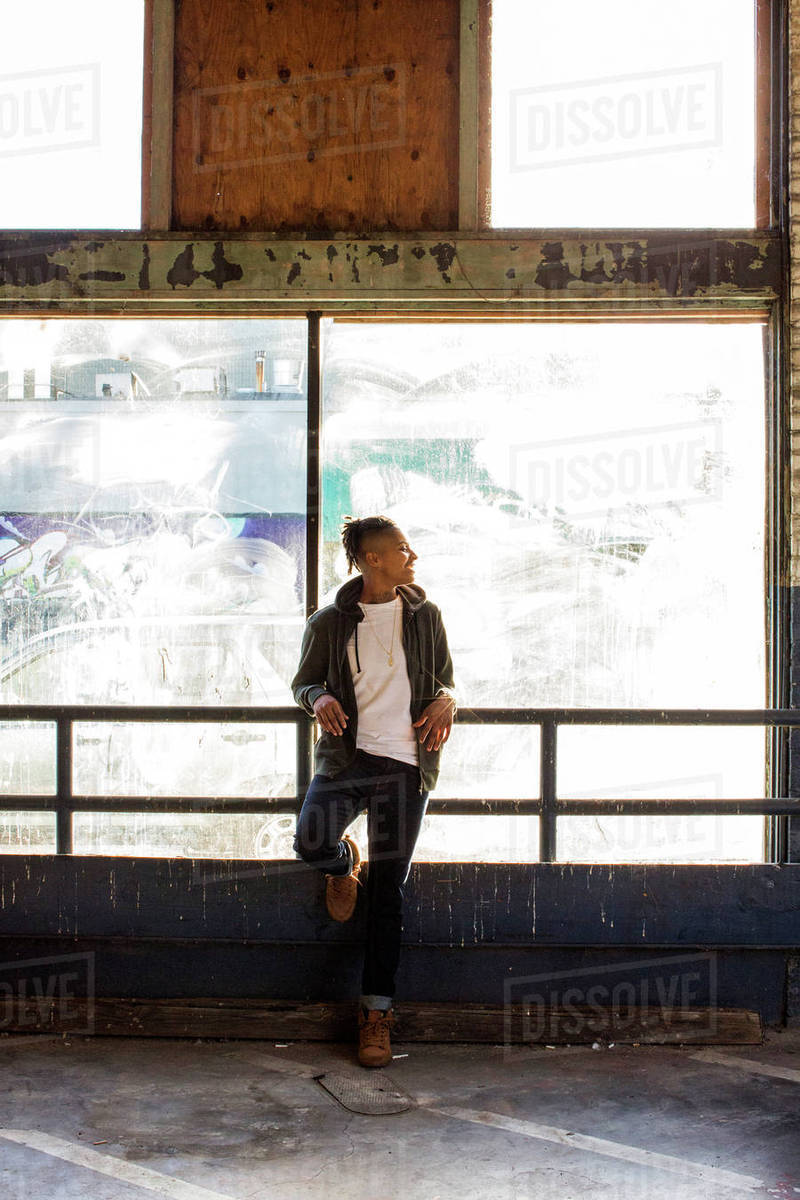 Smiling Mixed Race woman leaning on railing near window - Royalty-free ...