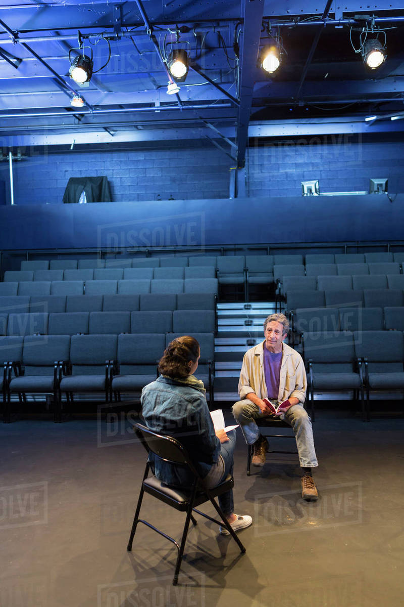 Actors rehearsing with scripts in theater - Stock Photo - Dissolve