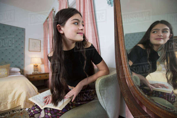 Girl reading book smiling in mirror - Royalty-free Stock Photo | Dissolve