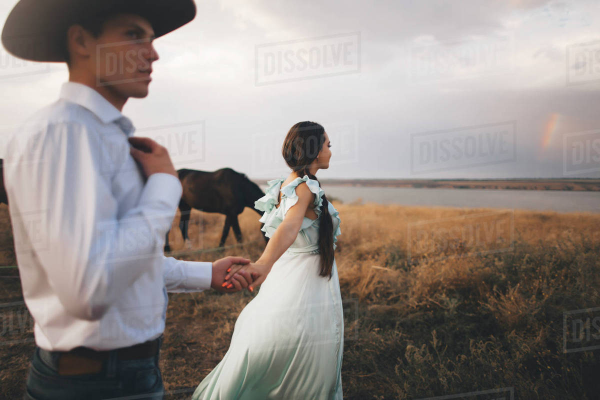 Woman holding hands with cowboy near river - Royalty-free Stock Photo ...