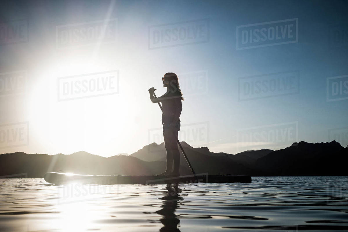 Silhouette of woman standing on paddleboard in river - Stock Photo ...