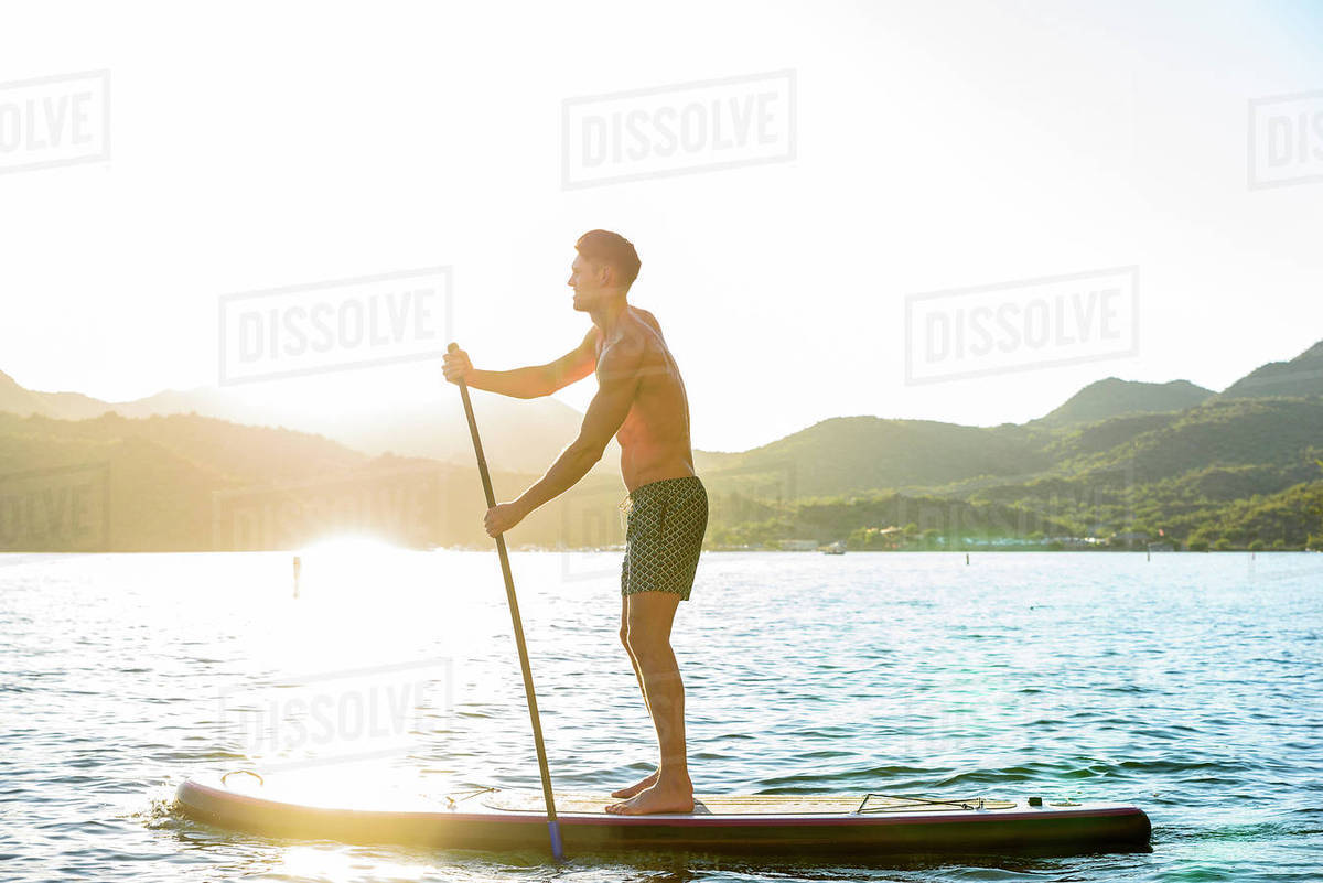 Man standing on paddleboard in river - Stock Photo - Dissolve