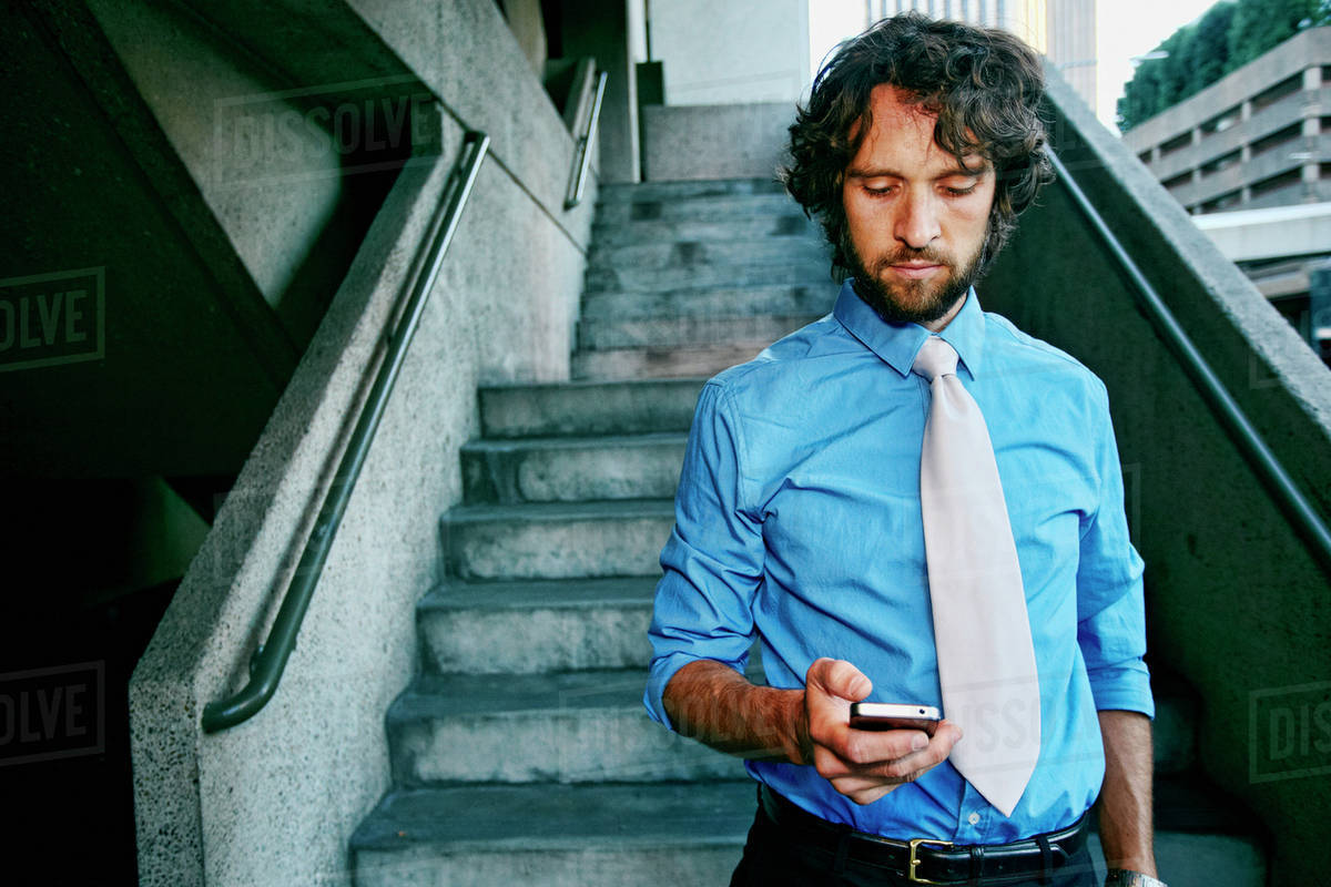 Caucasian businessman using cell phone on urban stairs - Royalty-free ...