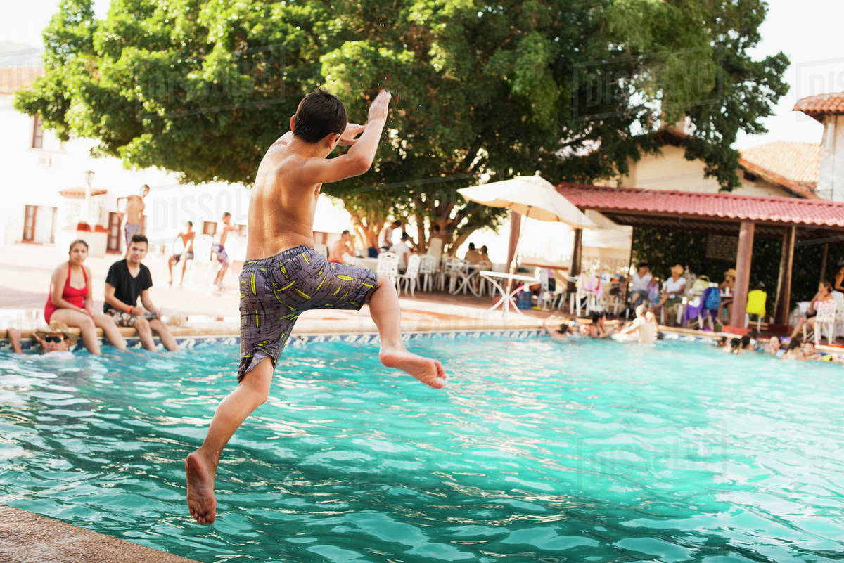 Mixed race boy jumping into pool - Royalty-free Stock Photo | Dissolve