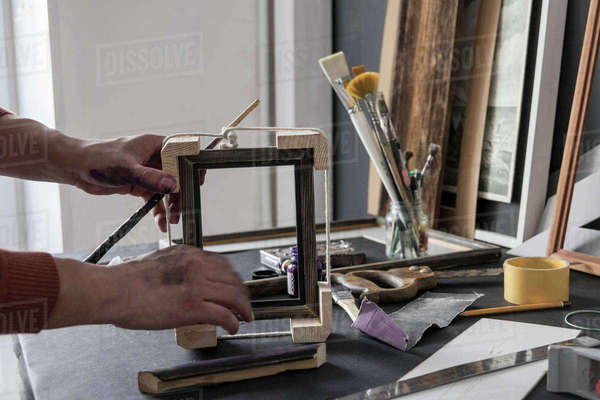 Hands of Caucasian artist making picture frame - Stock Photo - Dissolve