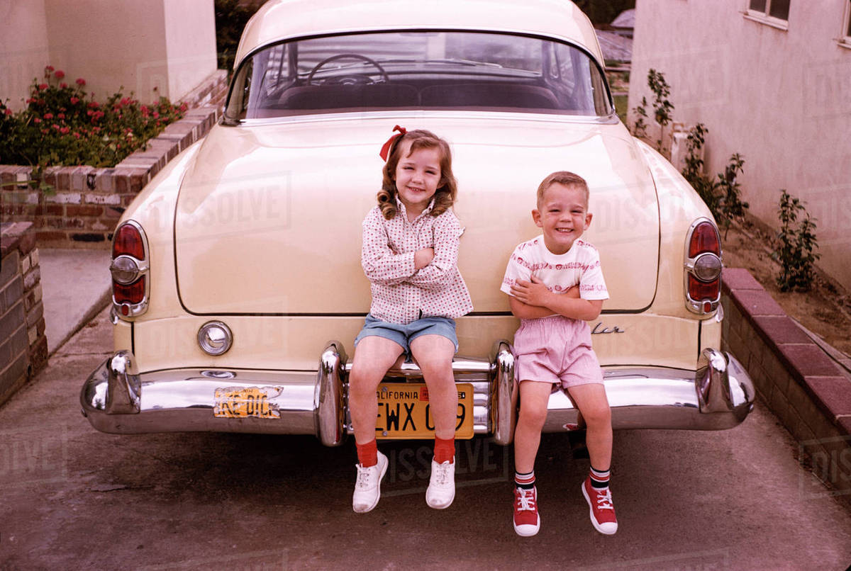 Caucasian brother and sister sitting on bumper of vintage car - Royalty ...