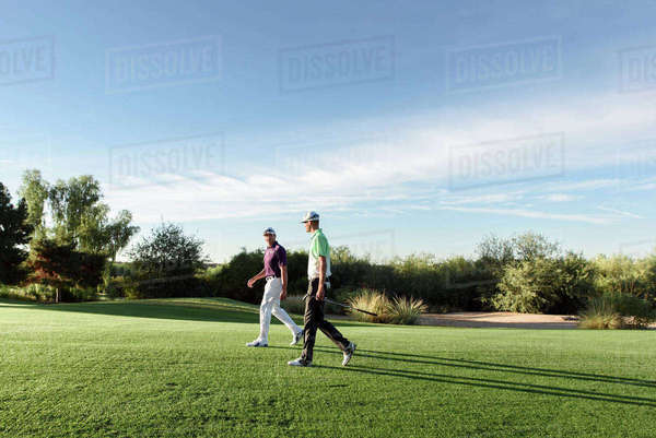 Friends walking on golf course - Stock Photo - Dissolve