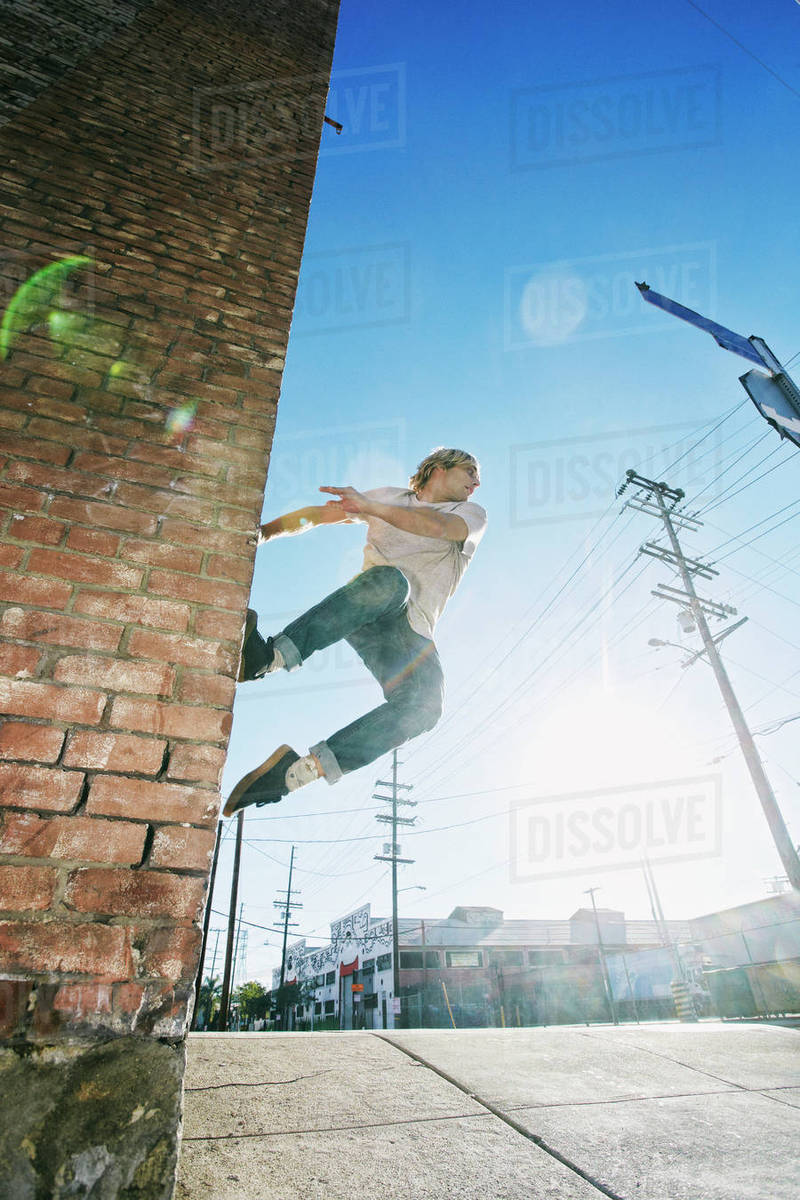 Caucasian man jumping on urban wall - Stock Photo - Dissolve