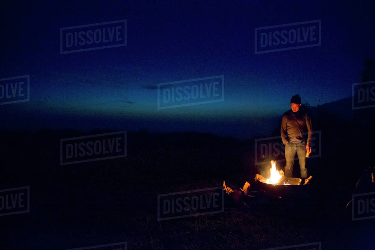 Caucasian man watching campfire at night - Royalty-free Stock Photo ...