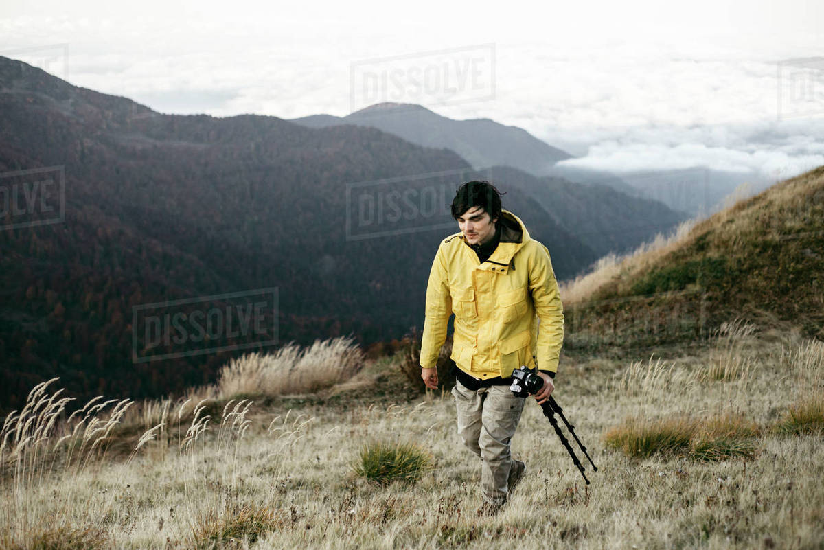 Caucasian man carrying tripod in remote mountain landscape - Royalty ...