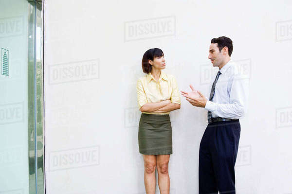 Business people talking near wall - Royalty-free Stock Photo | Dissolve