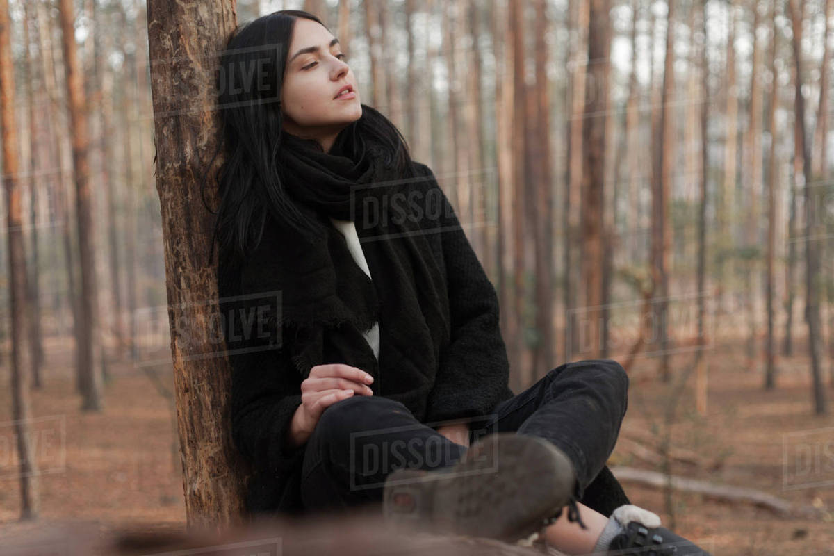 Pensive Caucasian woman sitting on log in forest - Royalty-free Stock ...
