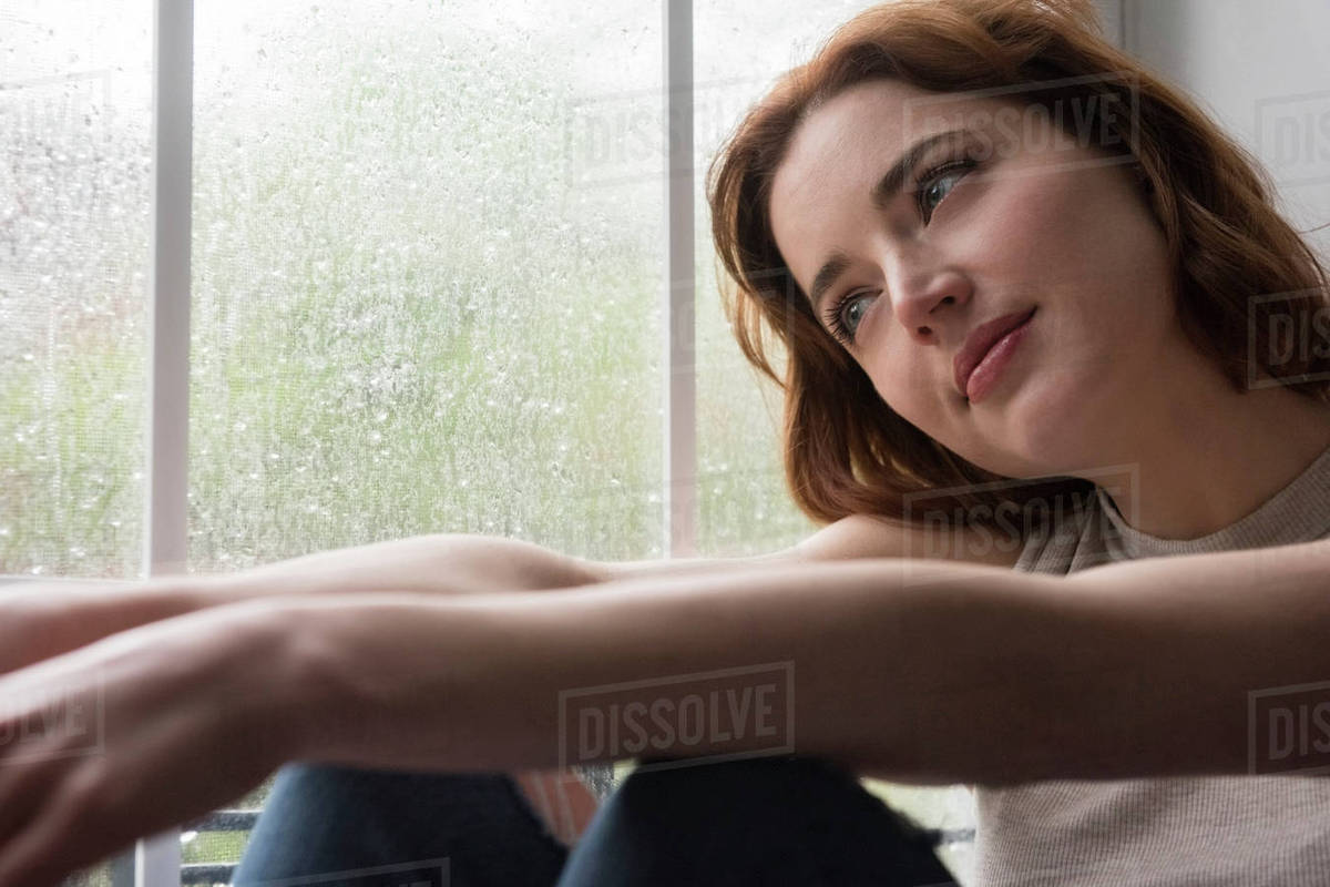 Caucasian woman sitting near rainy window daydreaming - Stock Photo ...