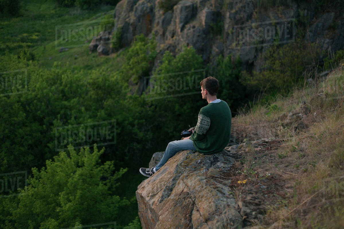 Caucasian man sitting on a rock admiring landscape - Royalty-free Stock ...