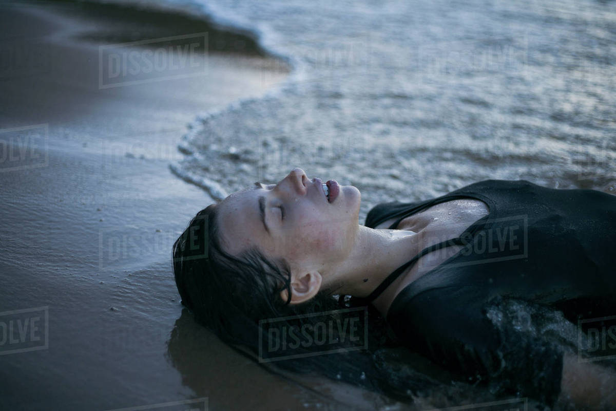 Caucasian woman laying on beach in waves - Royalty-free Stock Photo ...