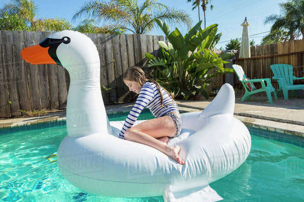 Caucasian girl sitting on inflatable swan in swimming pool - Royalty ...