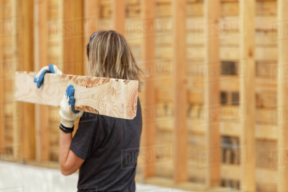 Caucasian woman carrying lumber at construction site - Royalty-free ...