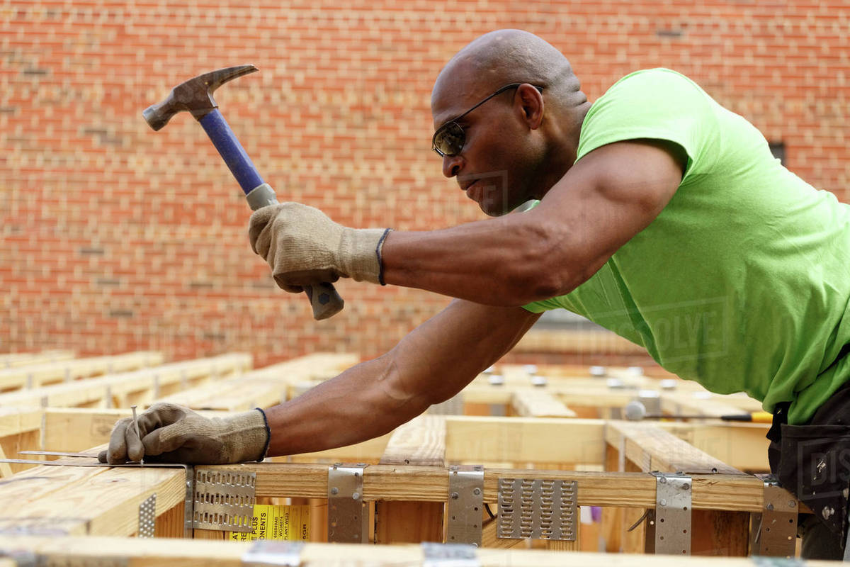 Black man hammering nail at construction site - Royalty-free Stock ...