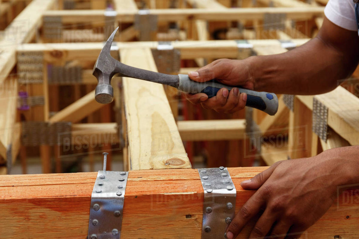 Mixed race man hammering nail at construction site - Stock Photo - Dissolve
