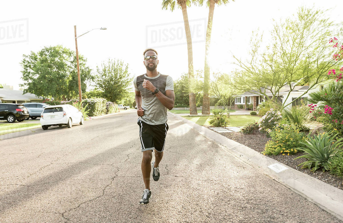 Black man running on street in neighborhood - Stock Photo - Dissolve