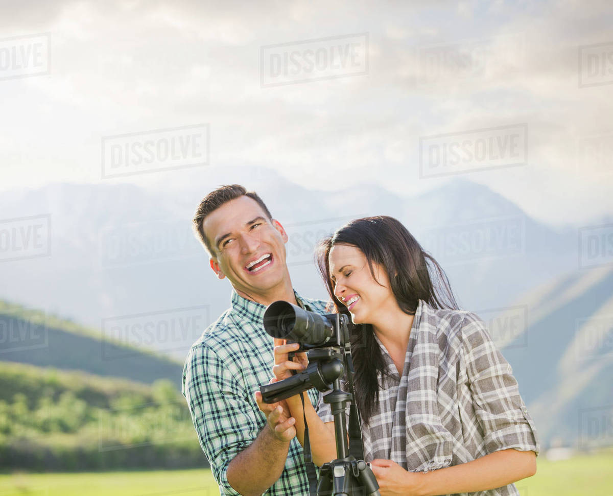 Couple with camera laughing - Stock Photo - Dissolve