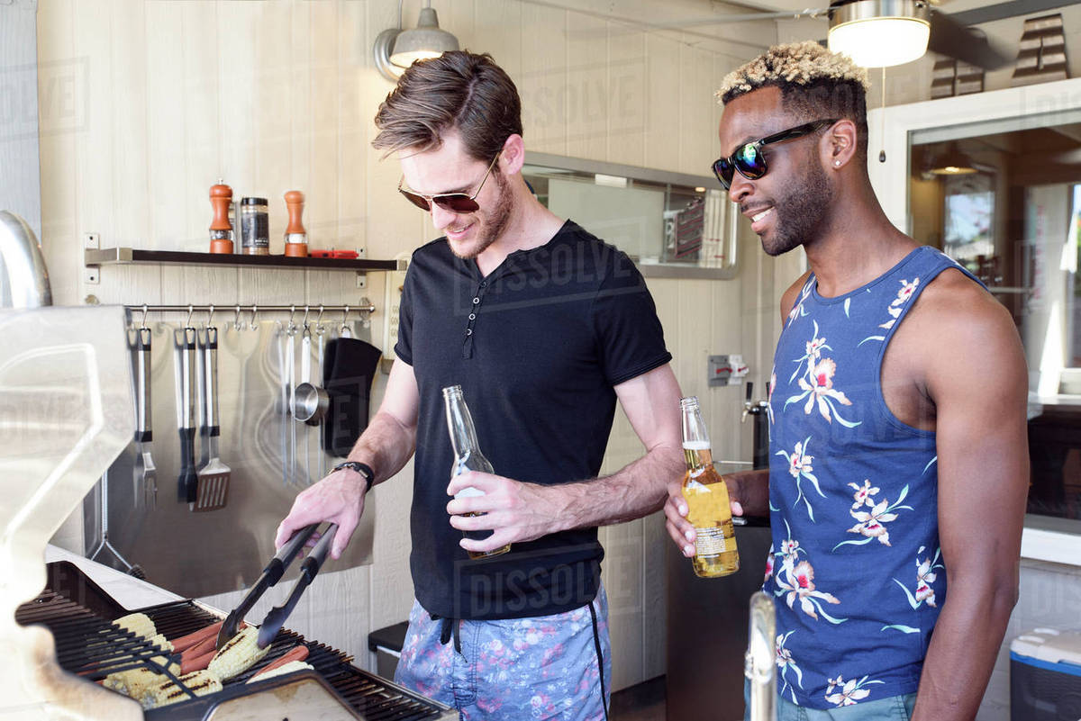 Men drinking beer and cooking on grille outdoors - Stock Photo - Dissolve